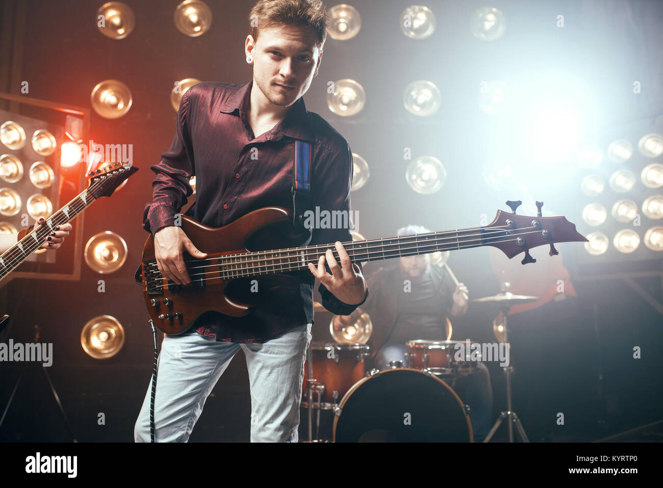 Guitarist plays on bas guitar, rock band, stage with lights on ...