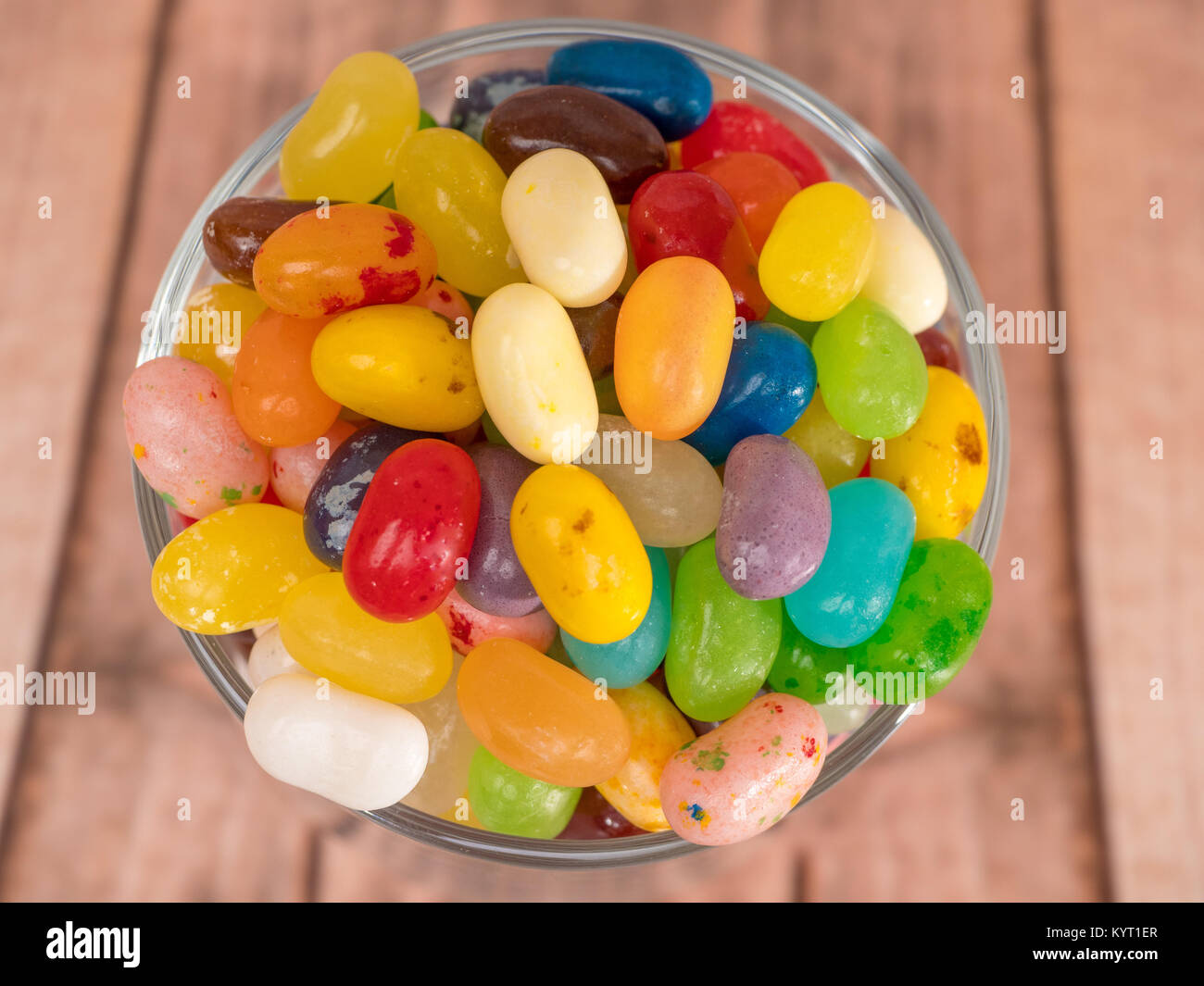 close up of multicoloured jelly beans in a glass on a wooden background ...