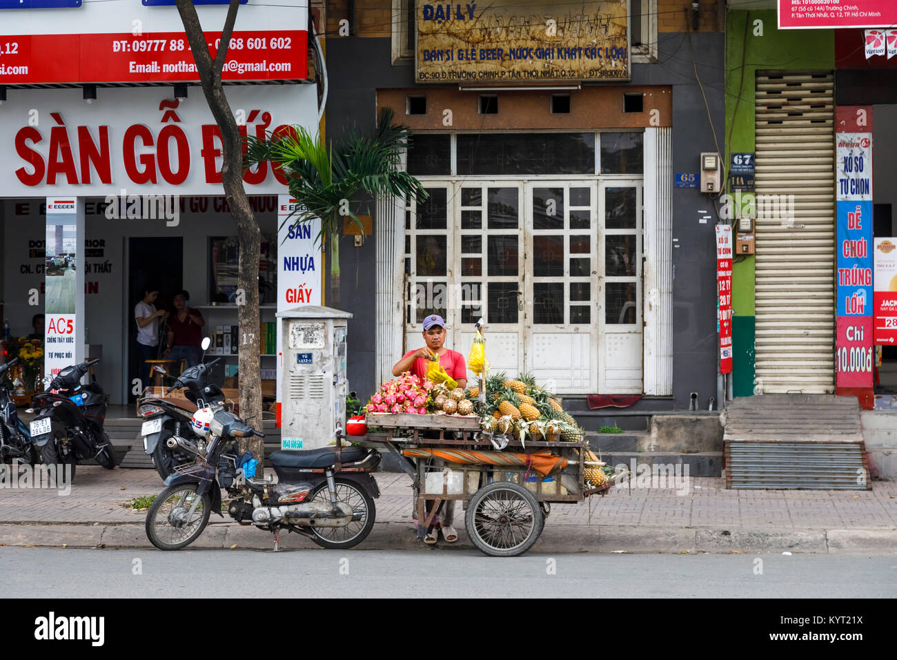 Stallholder at a roadside barrow stall selling fresh pineapples and ...