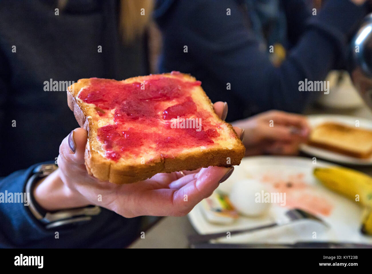 Hand holds a piece of bread with red jam Stock Photo - Alamy