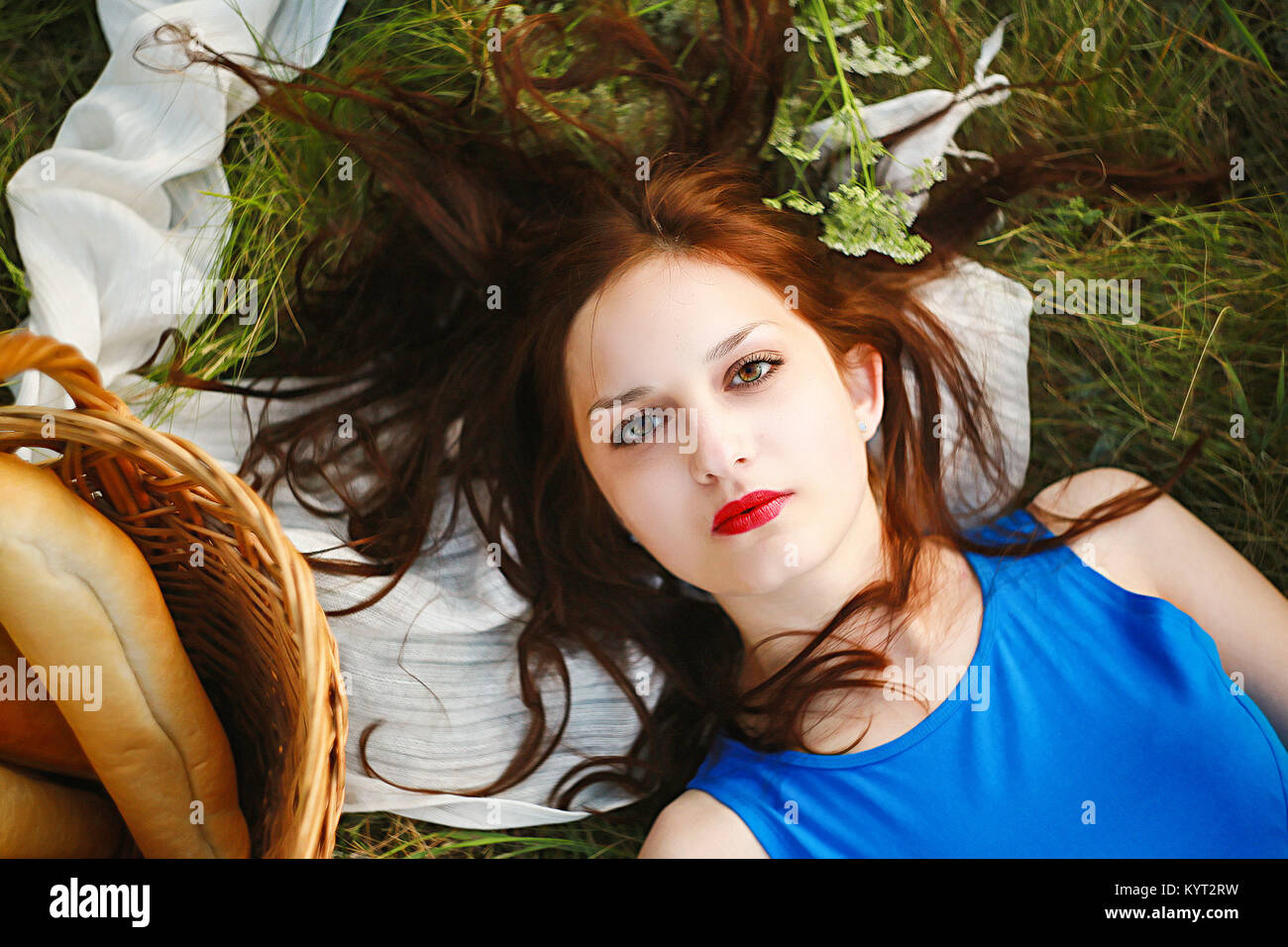 Beautiful girl lies on the grass with a basket and bread background ...
