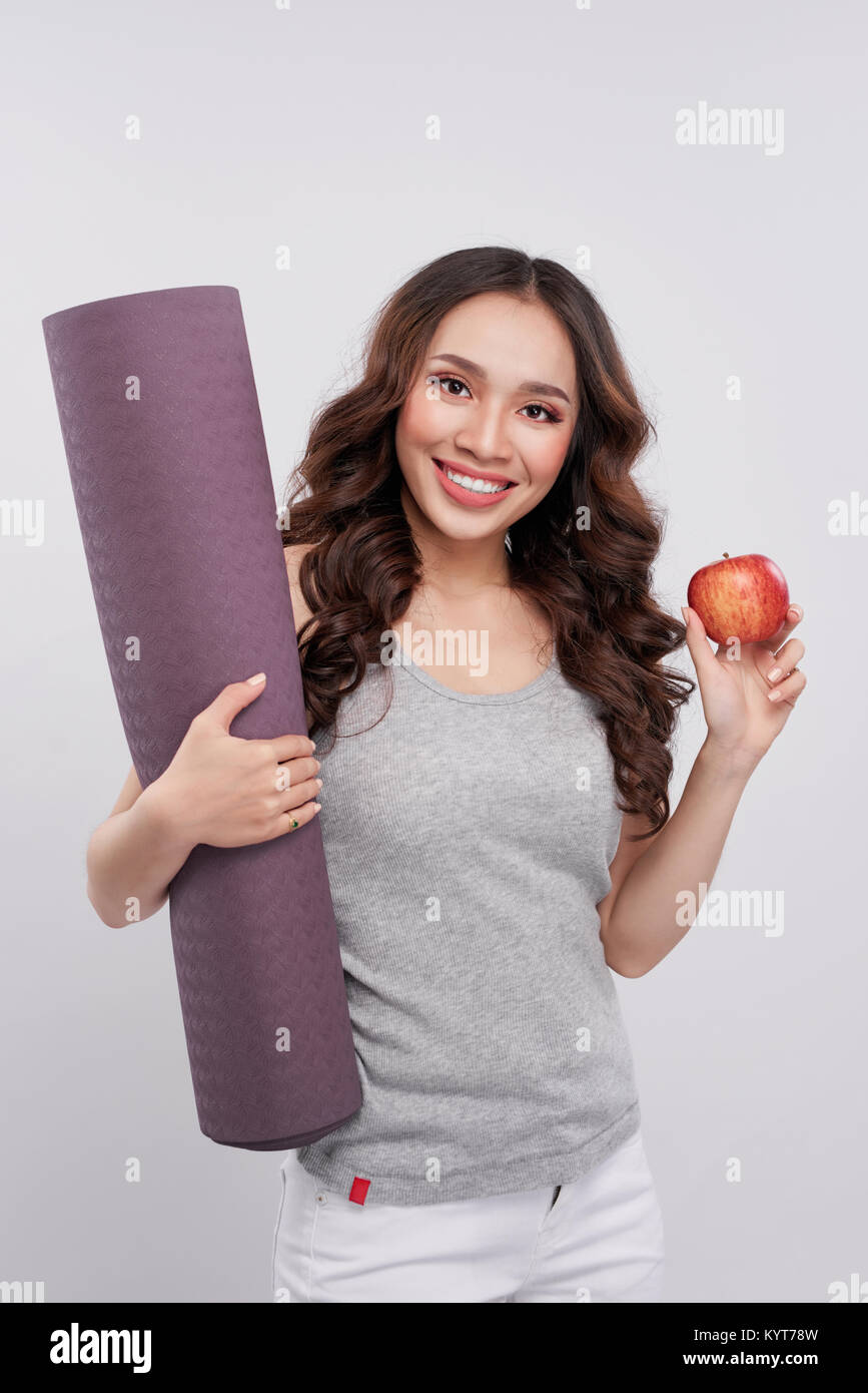 Beautiful woman with a yoga mat, hand holding red apple Stock Photo - Alamy