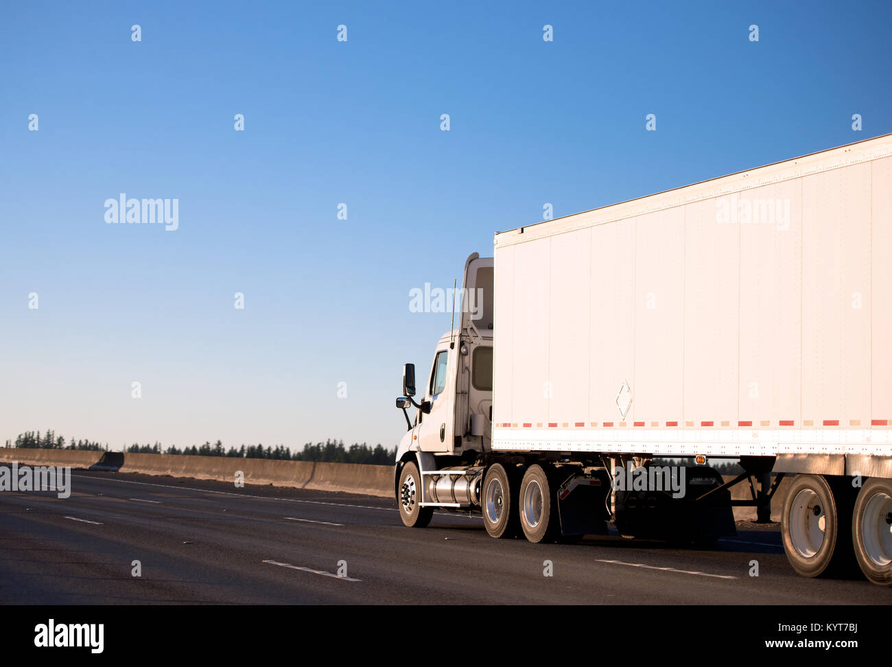 A modern powerful white big rig semi truck with a spoiler on a day cab ...