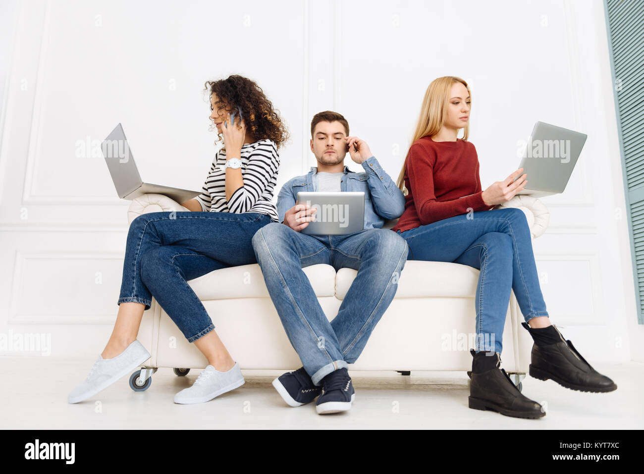 Full length photo of young people that sitting on sofa Stock Photo - Alamy