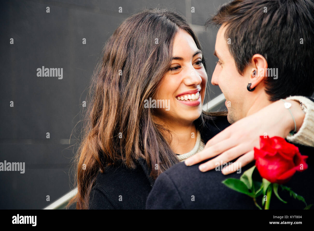 Pretty and happy couple in love cuddling on the street holding a red ...