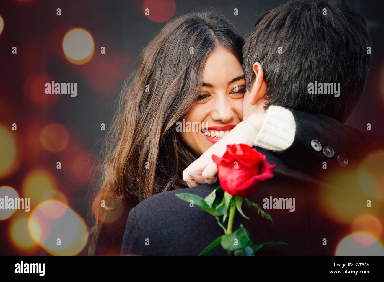 Pretty and happy couple in love cuddling on the street holding a red ...