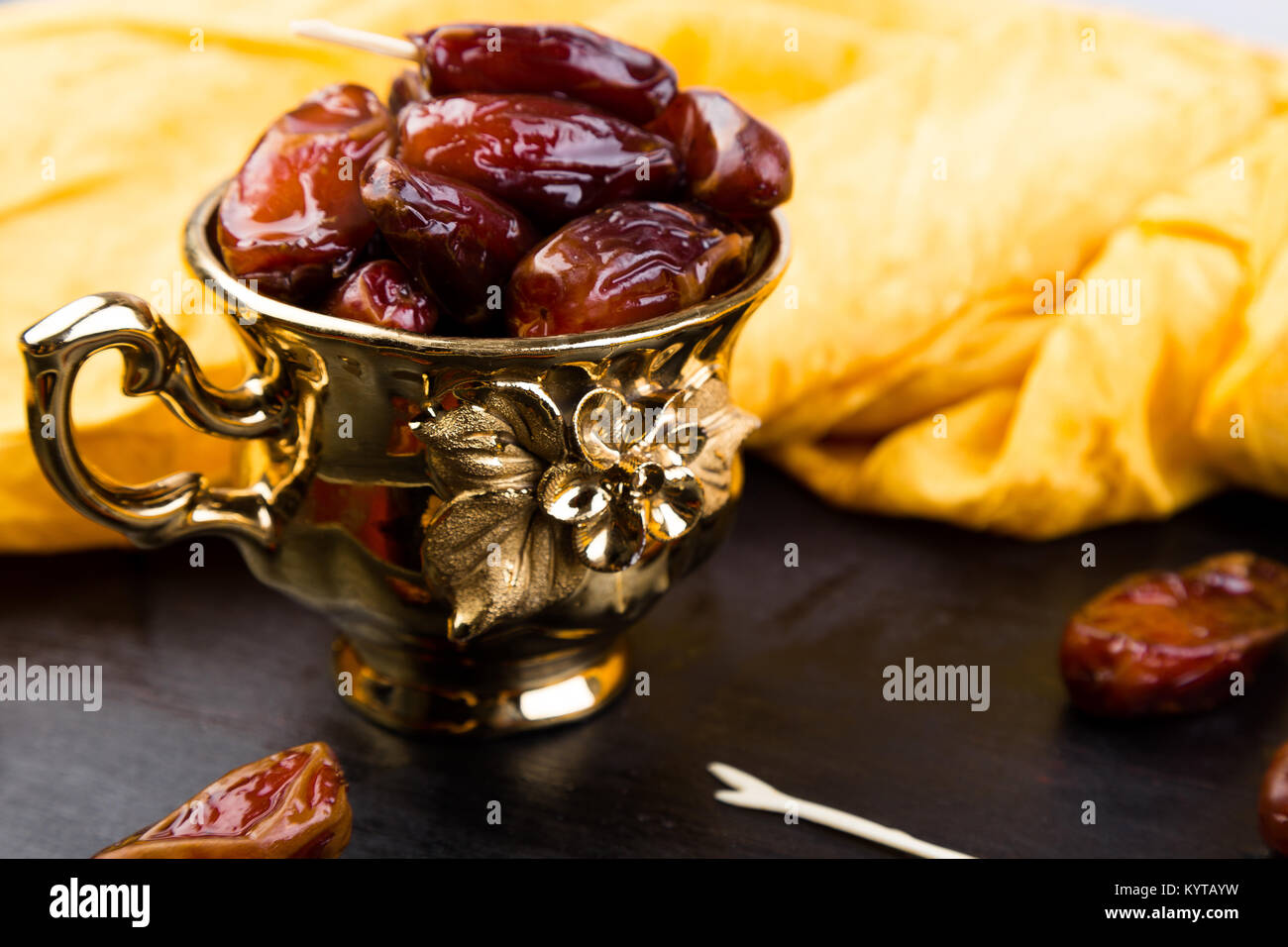 Dry fruit dates in golden cup near slate black heart. Copy space Stock ...
