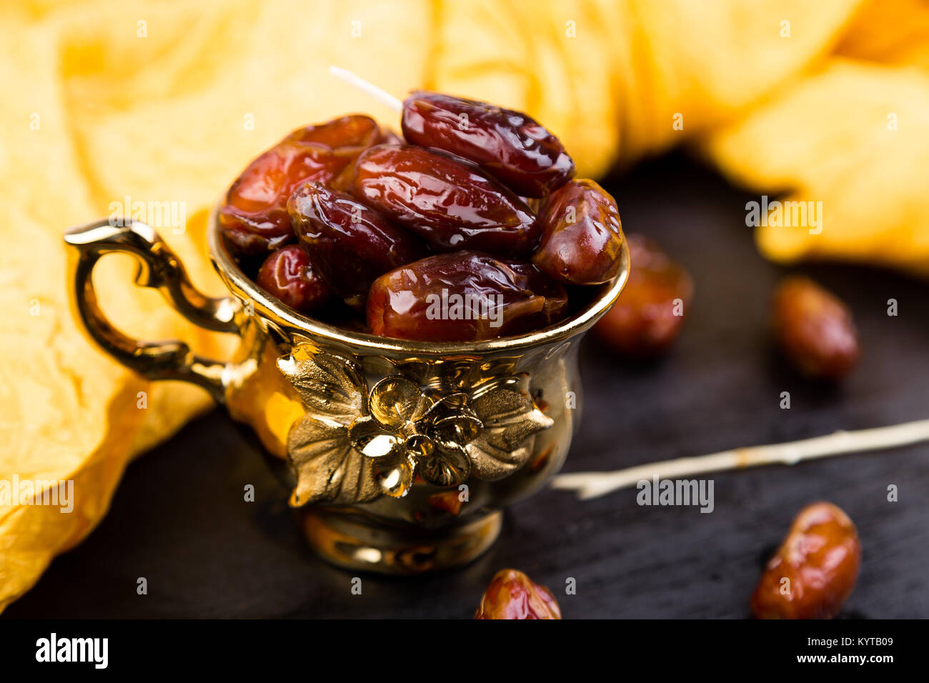 Dry fruit dates in golden cup near slate black heart. Copy space Stock ...