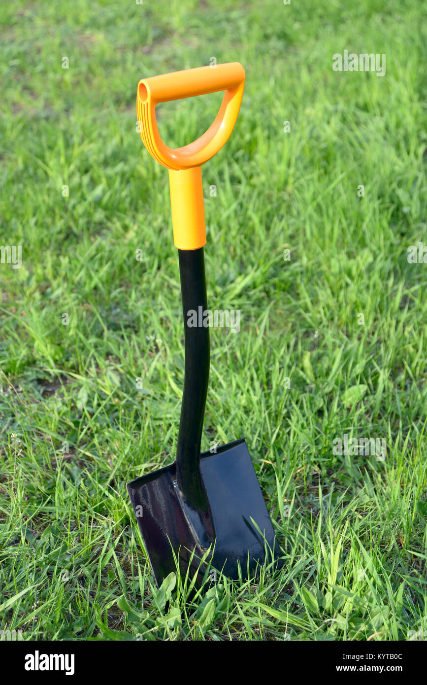 Shovel stuck in the grass lawn Stock Photo - Alamy