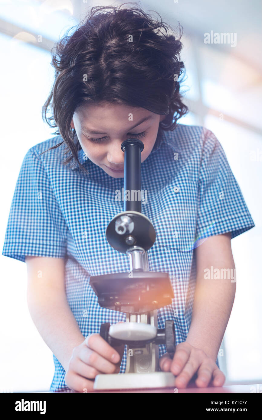 Enlarging lens. Logical hardworking clever kid using special equipment ...