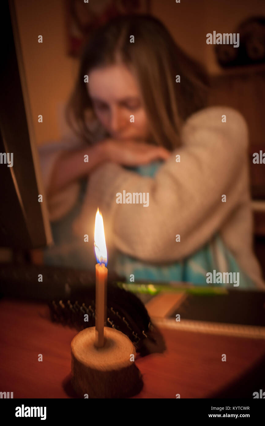 Blurred image with soft focus. Burning candle and sad sitting girl ...