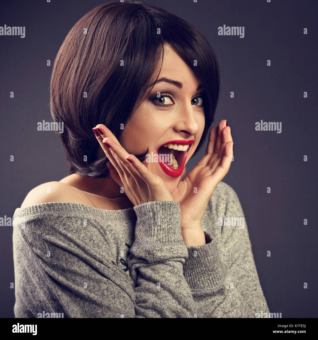 Surprising very excite woman looking with open mouth on dark grey ...