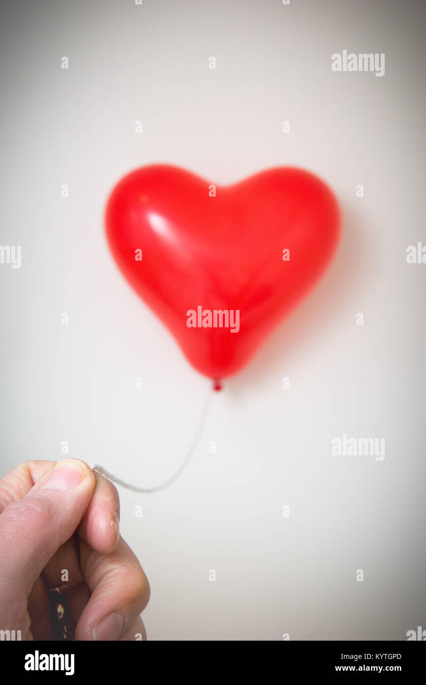 Male hand holding a red heart shaped balloon Stock Photo - Alamy