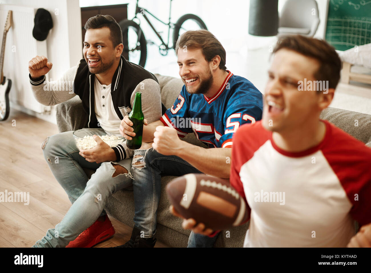 Excited football fans watching american football Stock Photo - Alamy