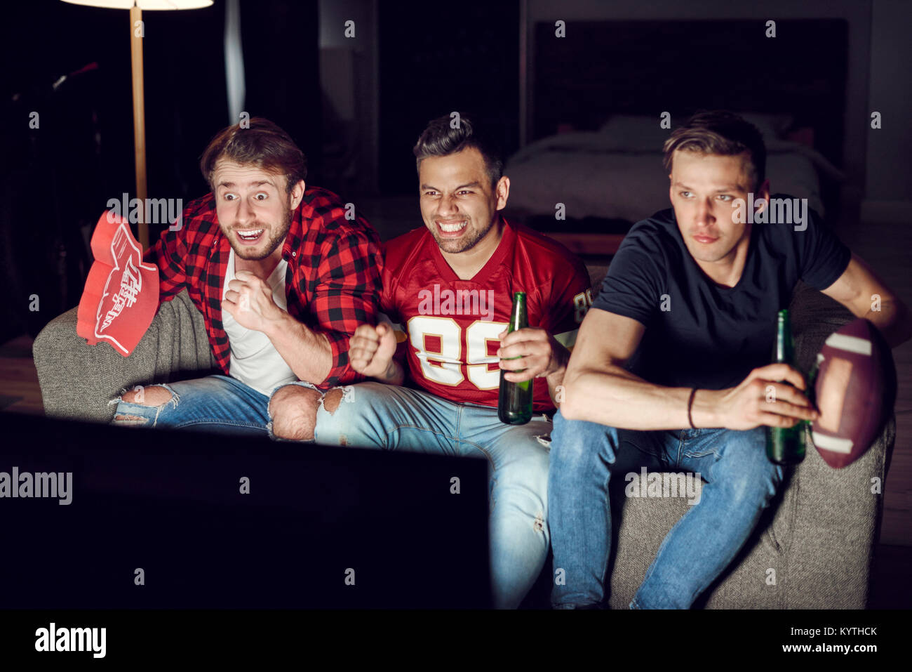 Excited football fans watching american football in the evening Stock ...