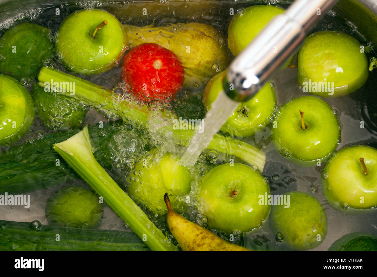 Washing fruit and vegetables in the kitchen sink before juicing and ...