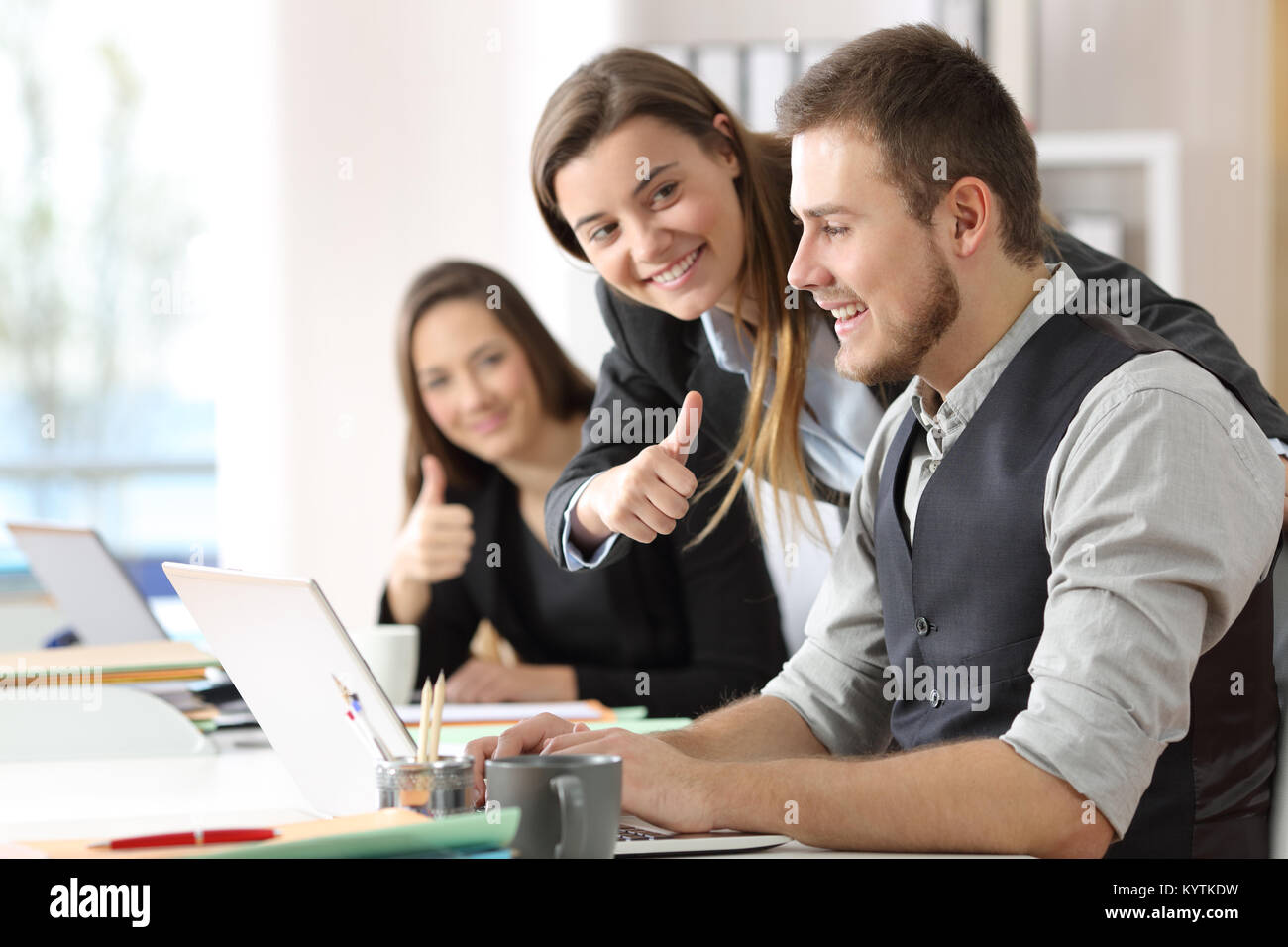Happy colleagues congratulating to a motivated worker after reaching ...