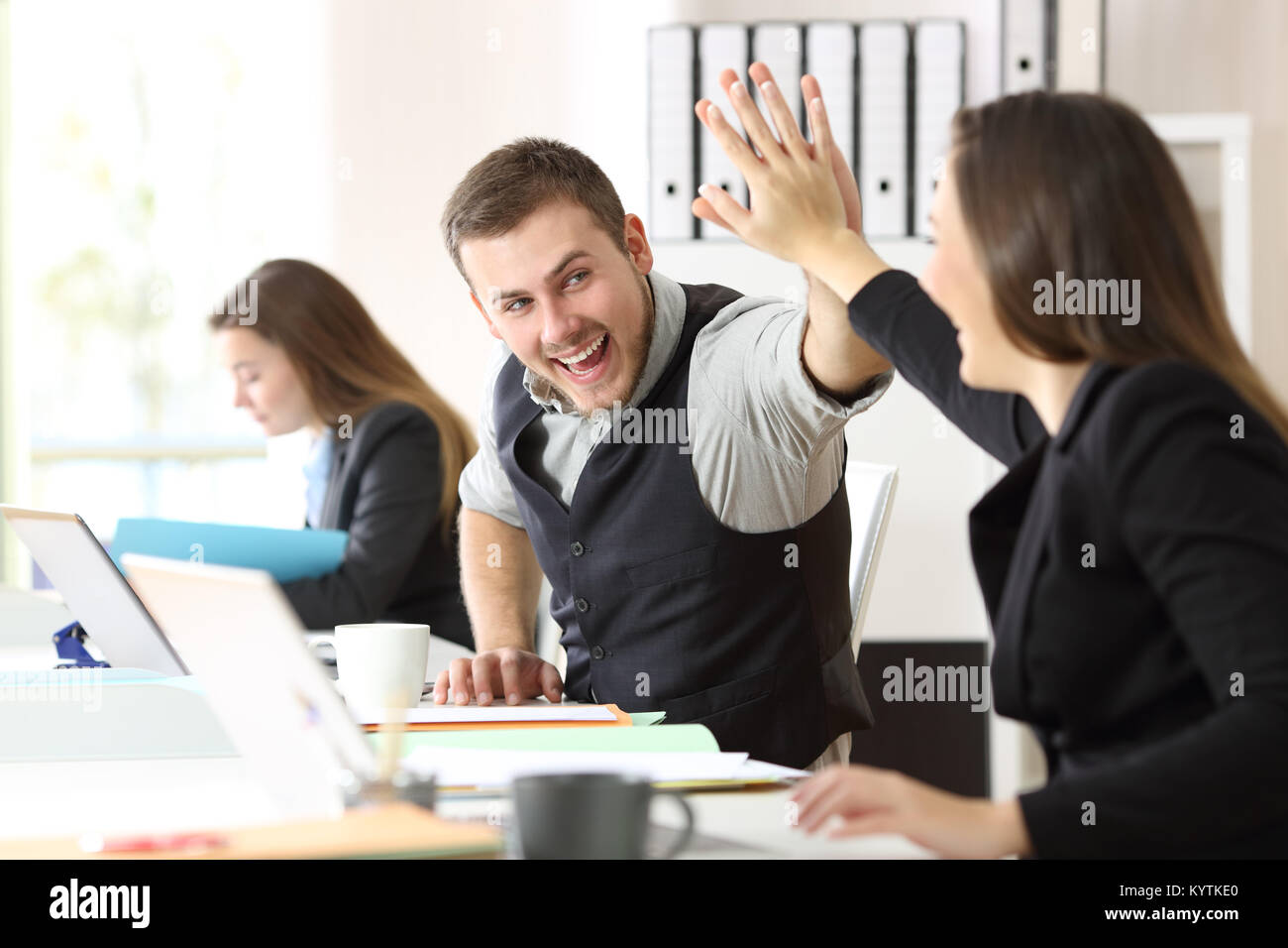 Two excited coworkers celebrating achievement giving five at office ...