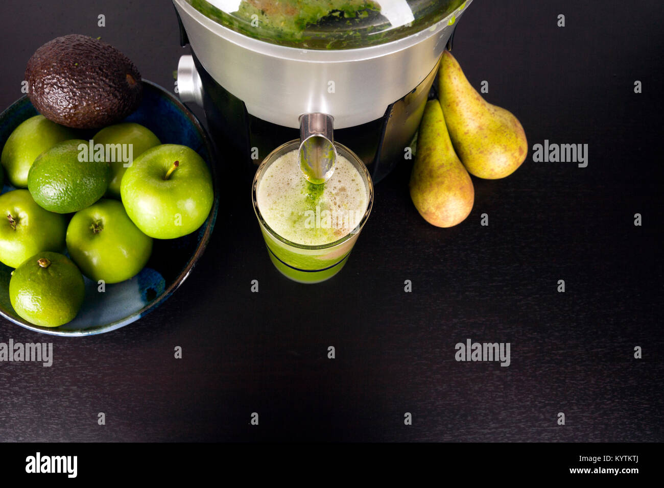 A juicer pouring fruit and vegetable juice into a drinking glass on a ...