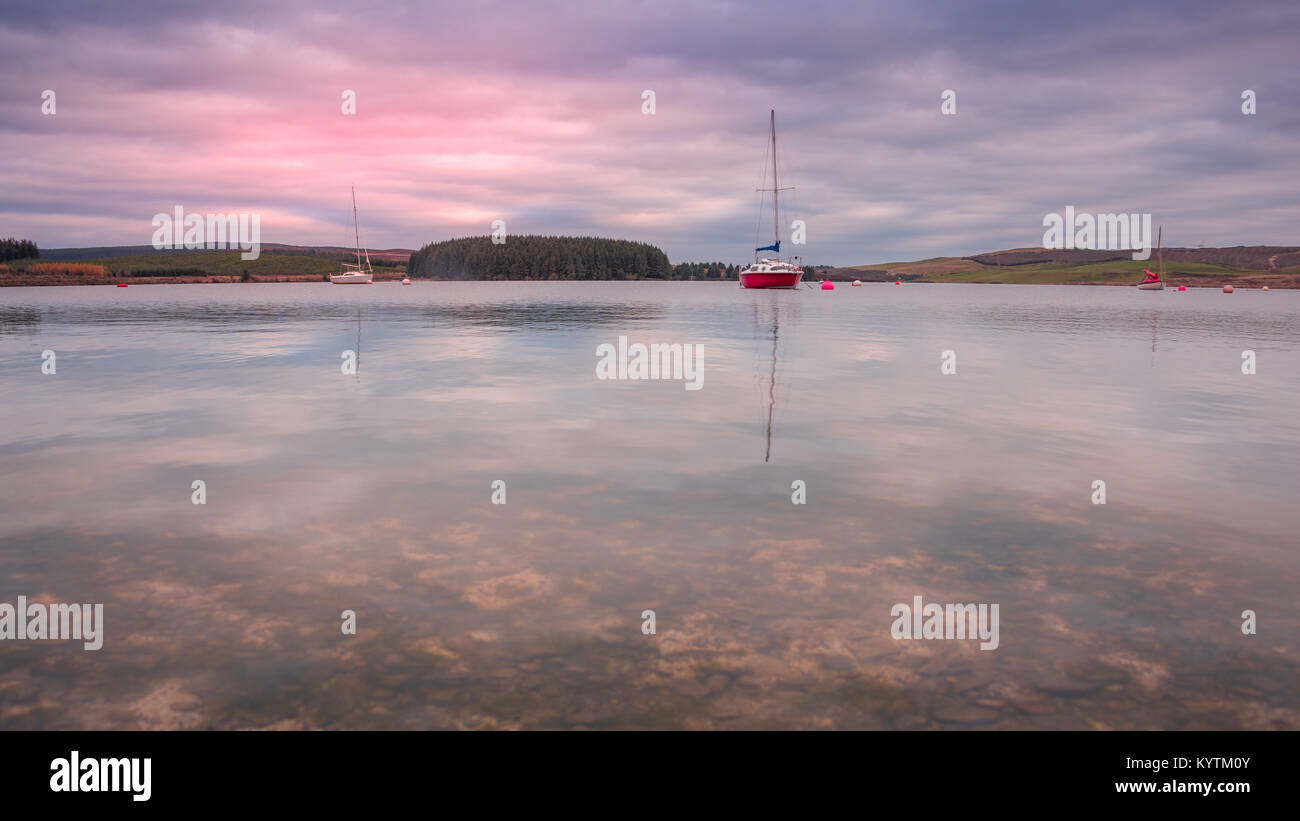 A low angle landscape of a sunrise over a peaceful lake with three ...