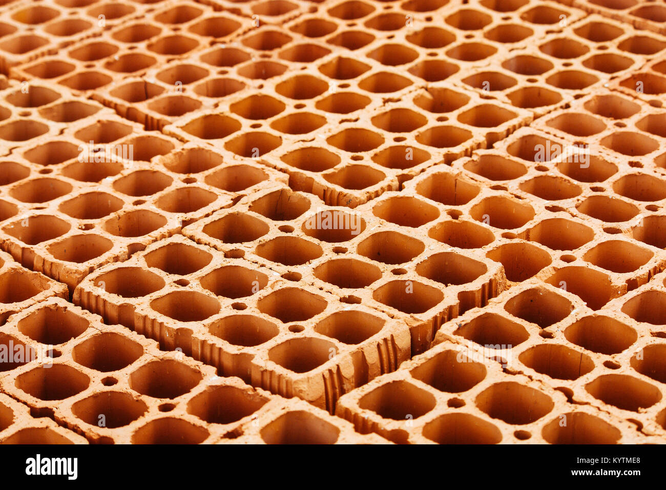 Pile of red hollow bricks with large holes forming a repetition ...