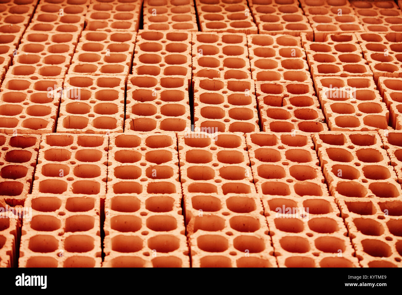 Pile of red hollow bricks with large holes forming lines in repeating ...