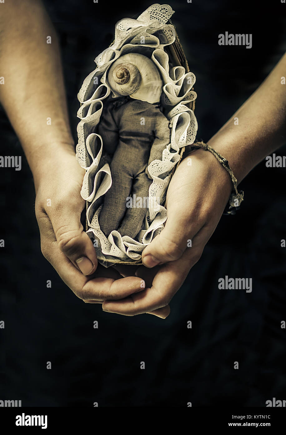Hands holding a miniature coffin containing a voodoo doll with shell ...