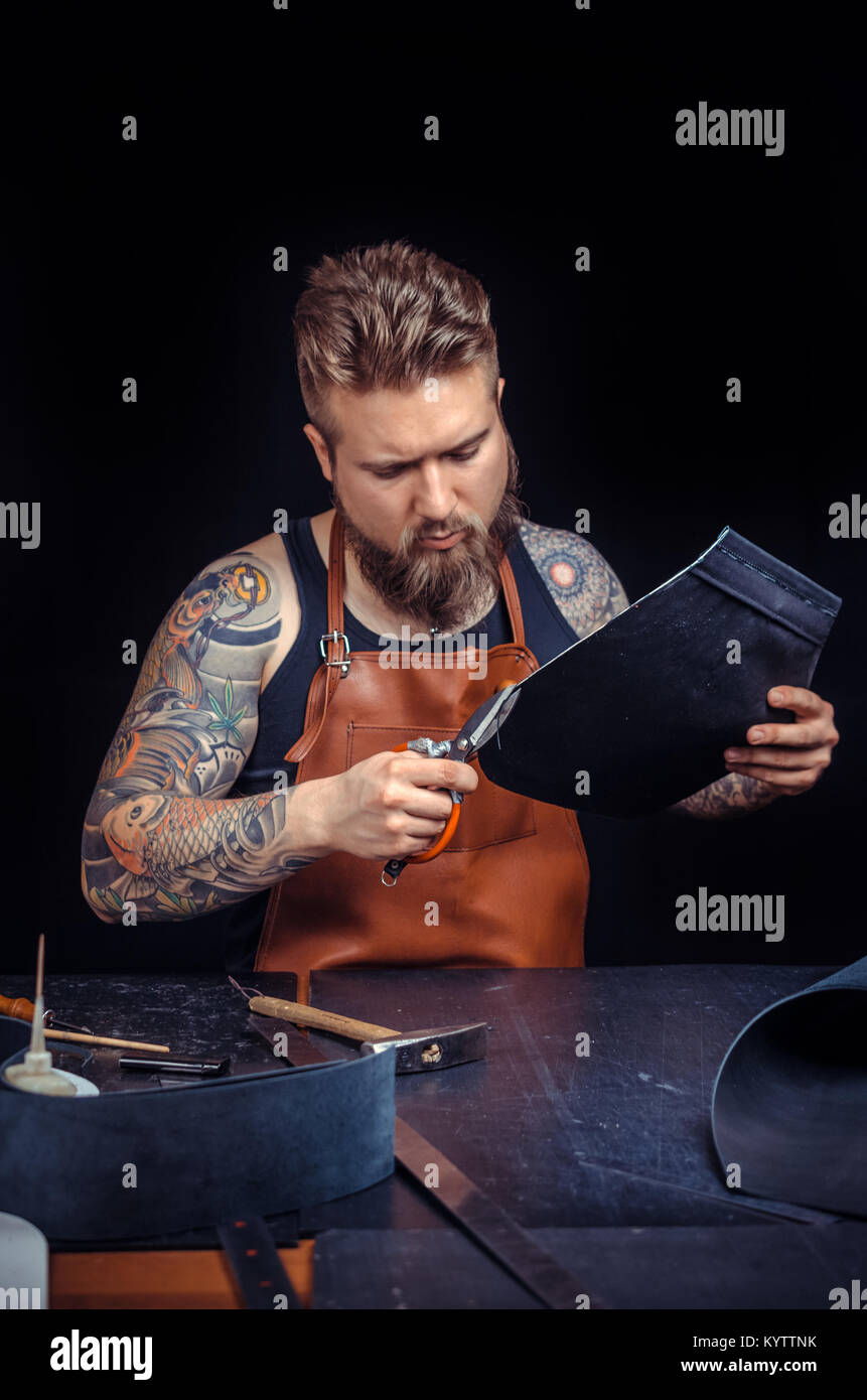 Leather Tanner working with leather using crafting tools in his shop ...
