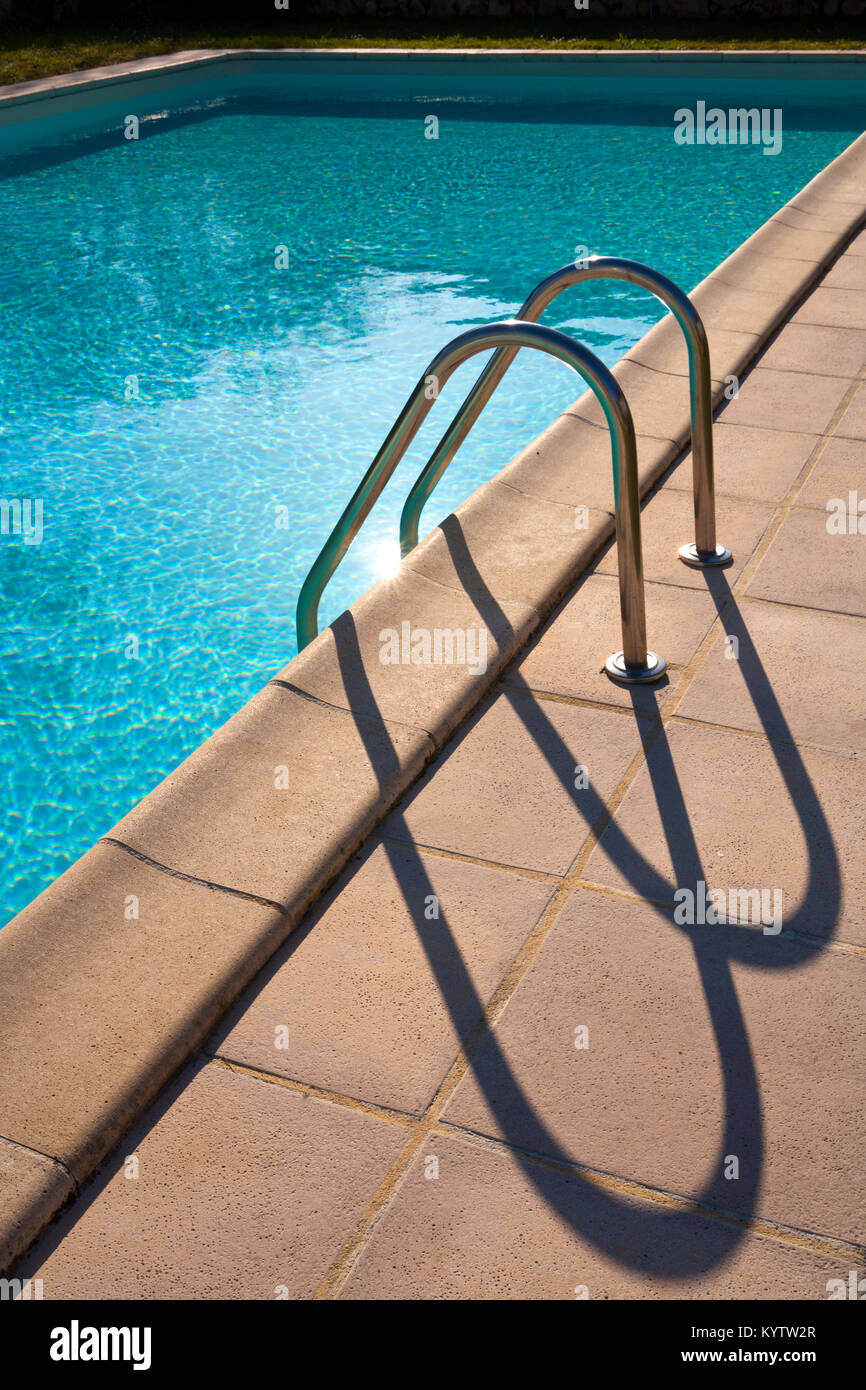 Graphic semi-abstract shape of outdoor swimming pool ladder shadows ...
