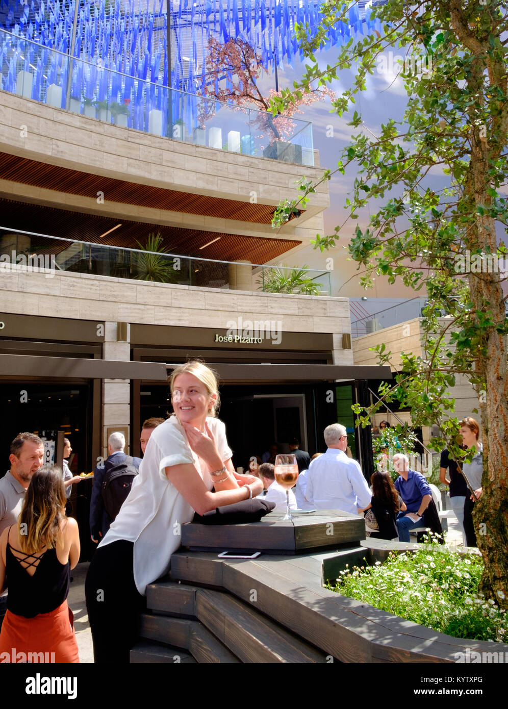 Young Lady smiles over her shoulder as she casually leans on the table ...