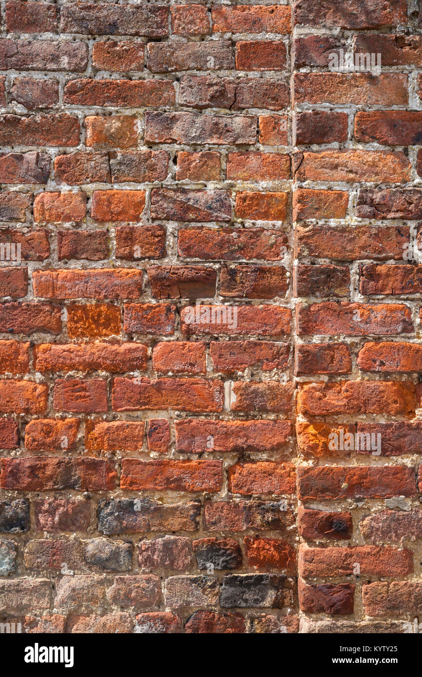 An old weathered, damaged, badly repaired red brick wall full frame ...