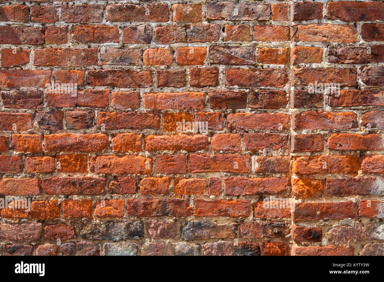 An old weathered, damaged, badly repaired red brick wall full frame ...
