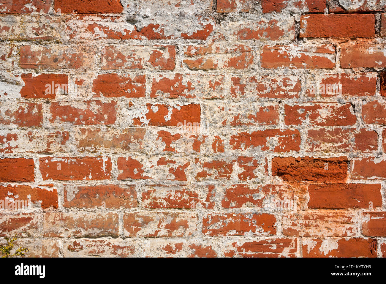 An old weathered, damaged, formerly painted, badly repaired red brick ...