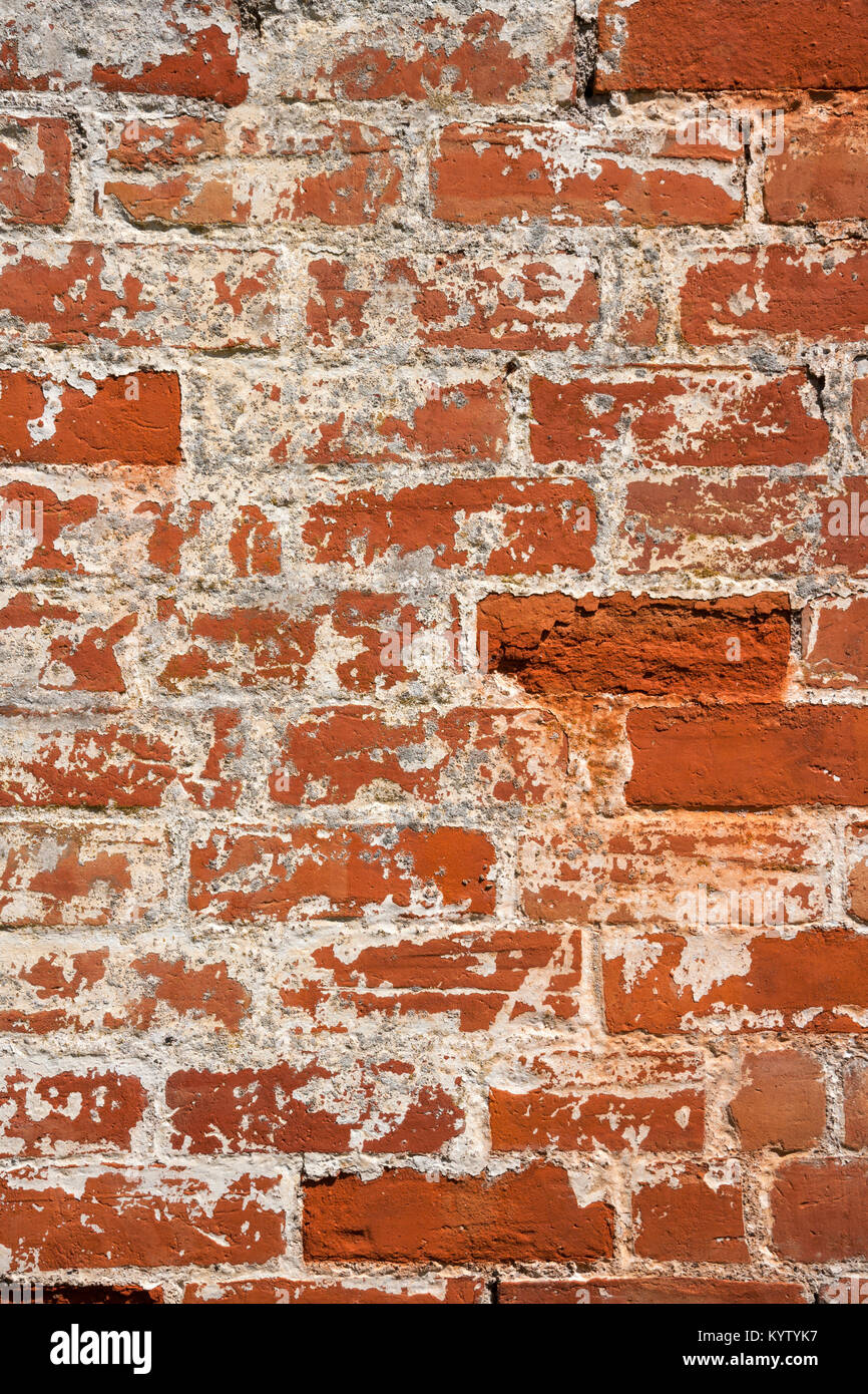 An old weathered, damaged, formerly painted, badly repaired red brick ...