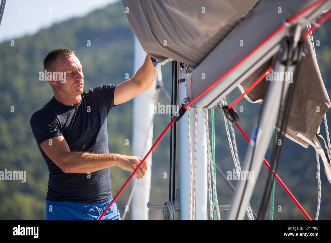 A young male sailor setting sail on his yacht Stock Photo - Alamy