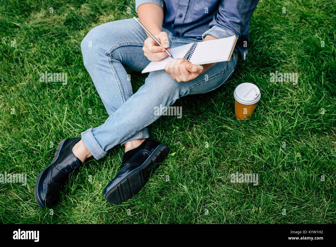 Cropped shot of man writing on notebook and drinking coffee from paper ...