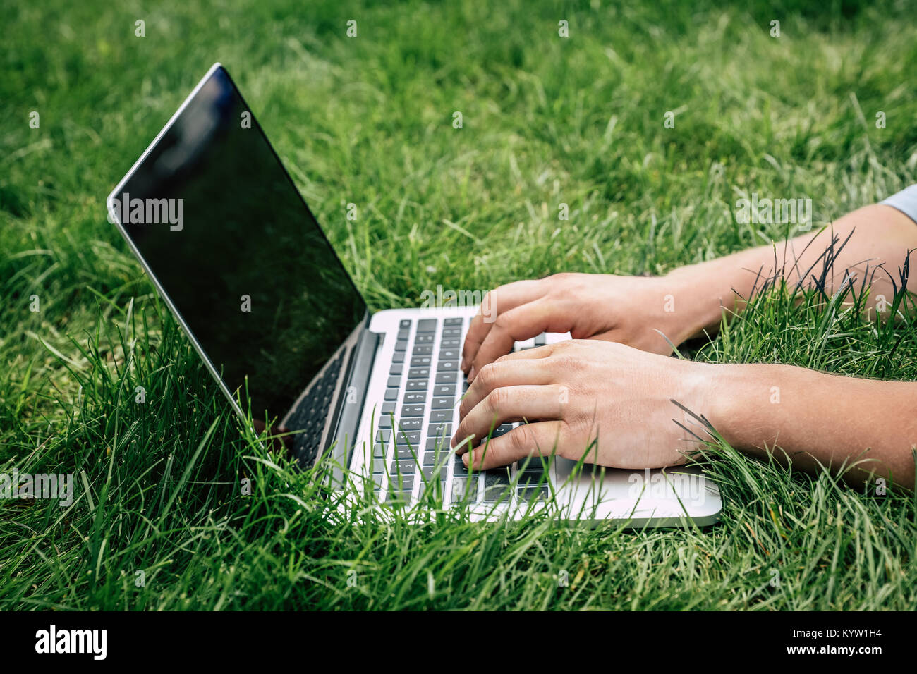 Cropped shot of person typing on laptop with blank screen outdoors ...