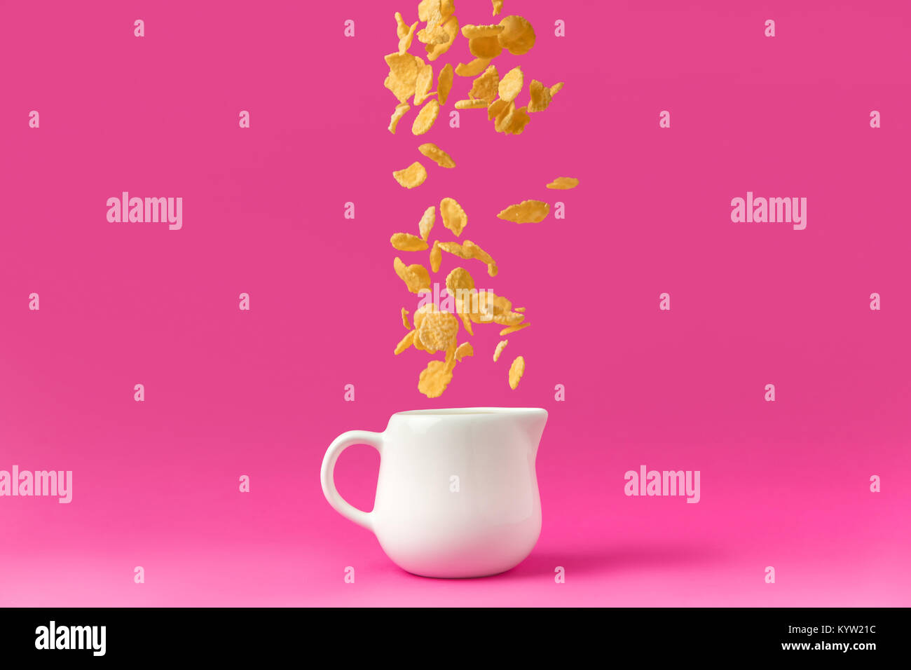 close-up view of organic corn flakes falling into milk jug isolated on ...