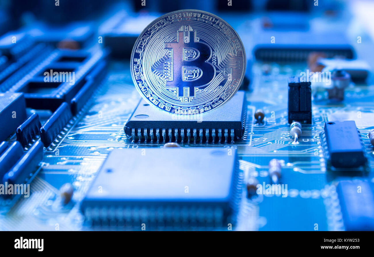 On a printed circuit motherboard is silver coin of a digital crypto ...