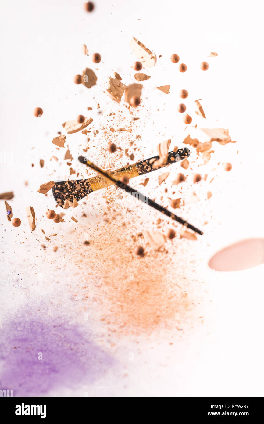 crushed cosmetic powder with makeup brushes falling isolated on white ...
