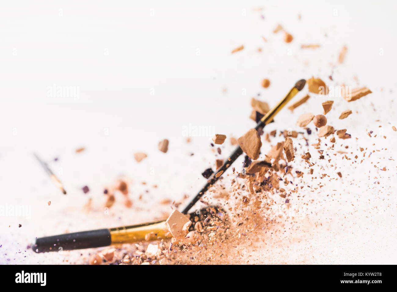 pieces of cosmetic powder with makeup brushes falling isolated on white ...