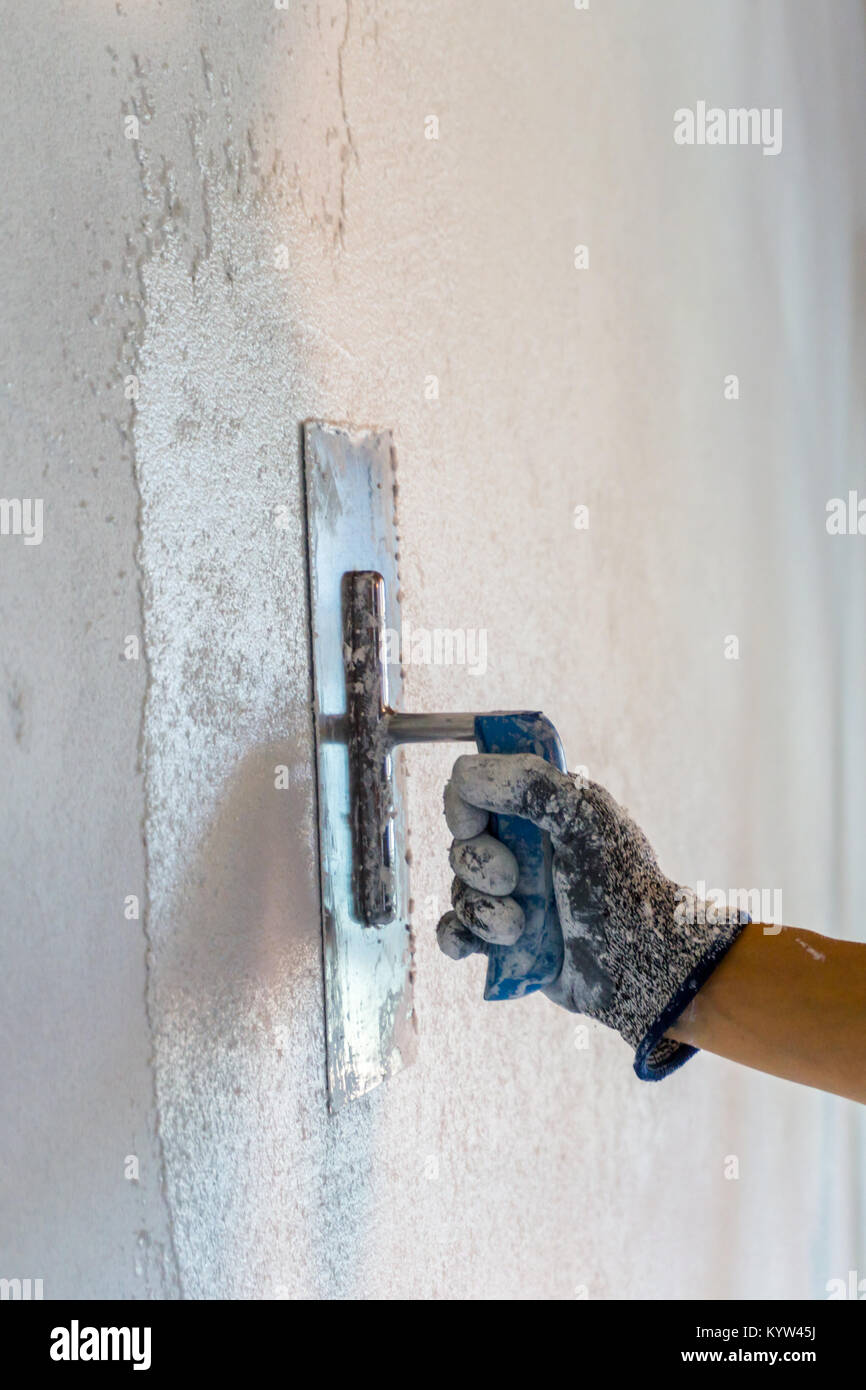 female hand of a plasterer applying fresh white plaster during ...