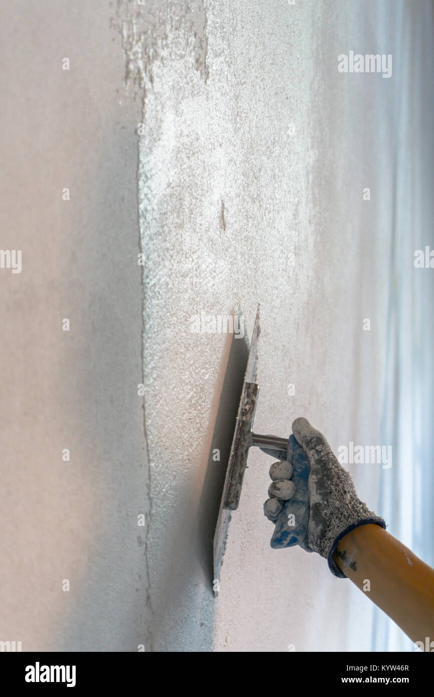 female hand of a plasterer applying fresh white plaster during ...