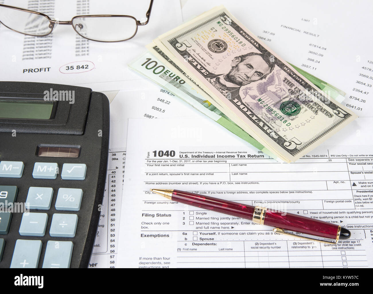 Calculating numbers for income tax return with pen, glasses and ...