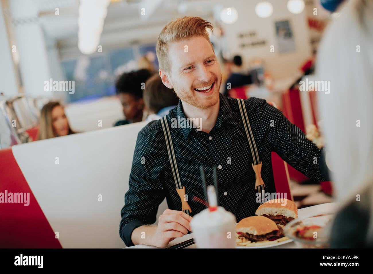 Young man eating beef cheeseburger in diner Stock Photo - Alamy