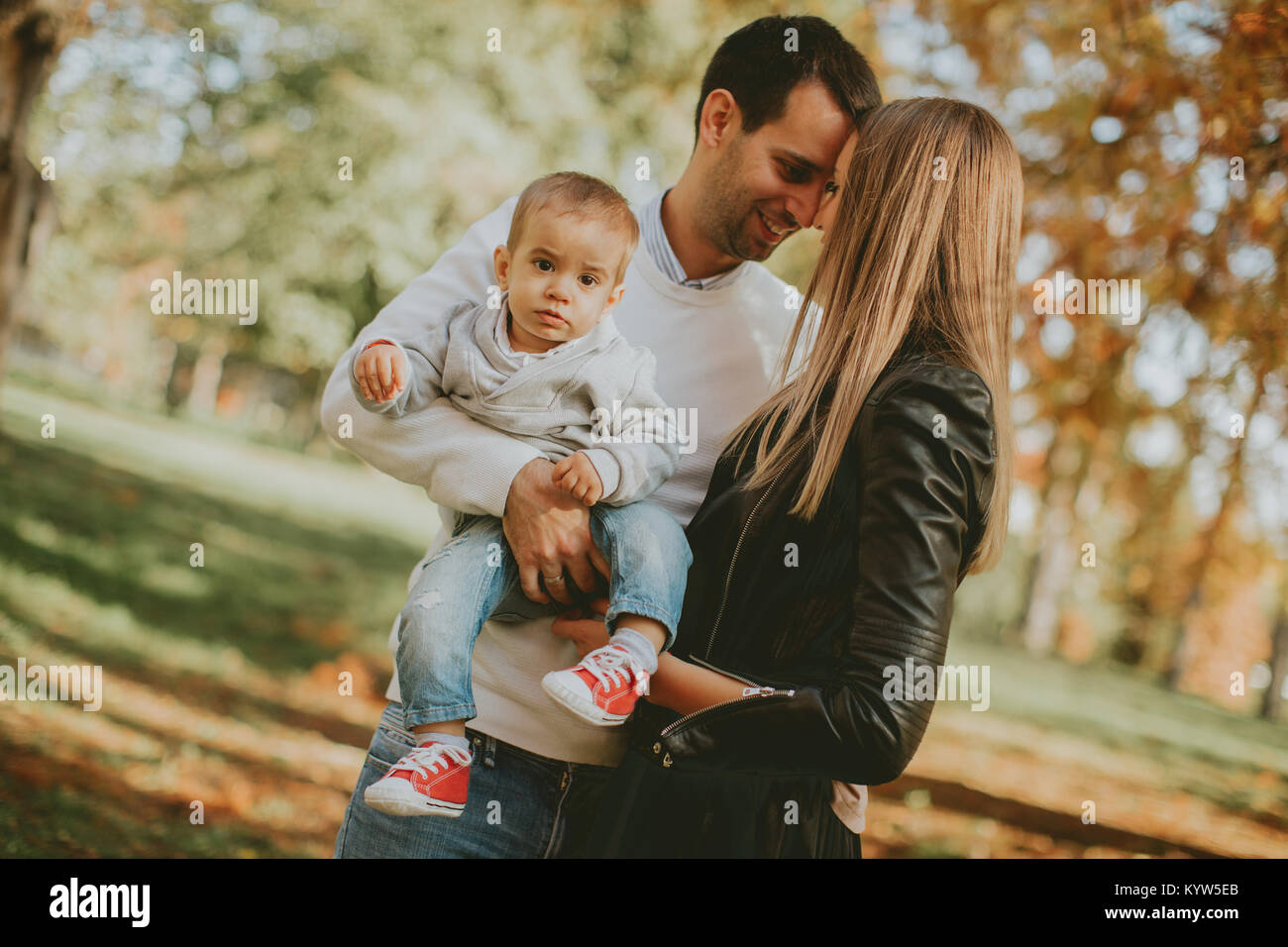 Happy young parents have fun with baby boy in autumn park Stock Photo ...