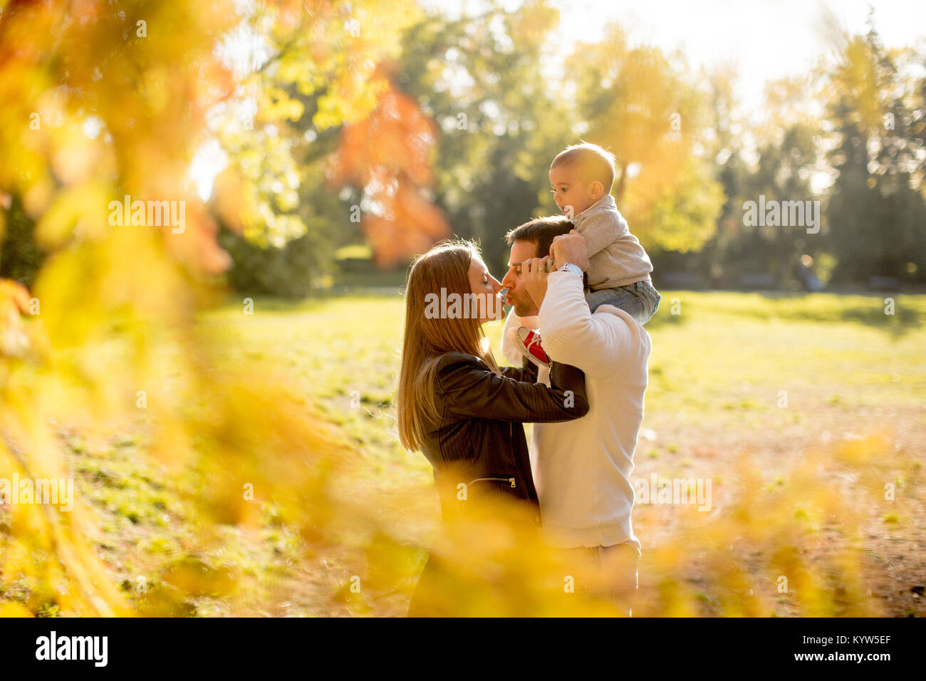 Happy young parents have fun with baby boy in autumn park Stock Photo ...
