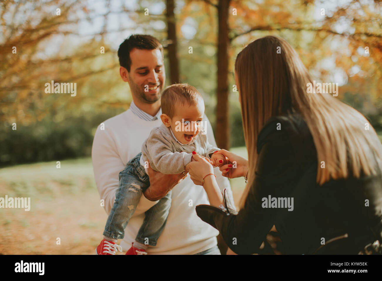Happy young parents have fun with baby boy in autumn park Stock Photo ...