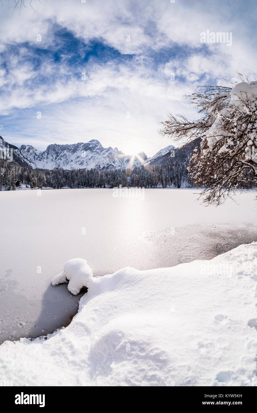 Mountain range Mangart seen from snow covert frozen lake Fusine with ...