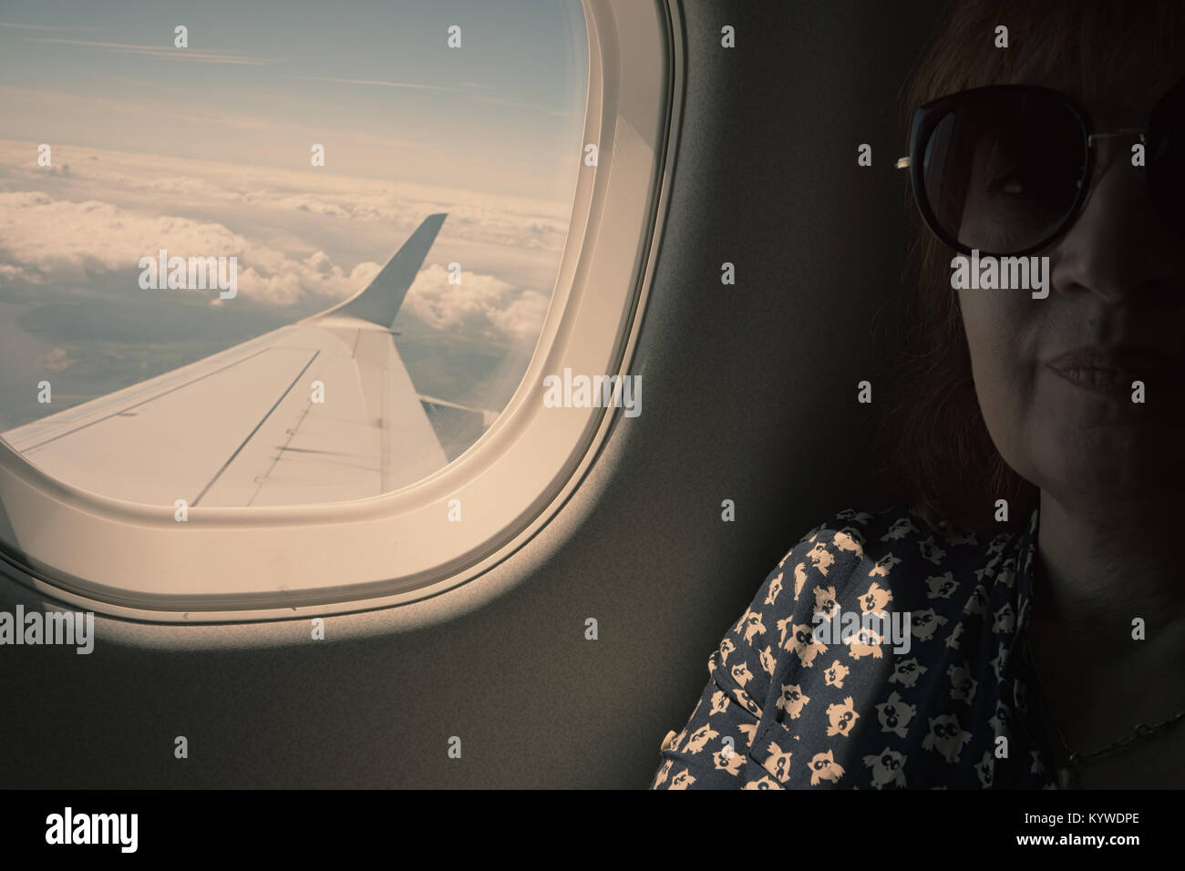 female passenger is sitting by the airplane window. The wing of the ...